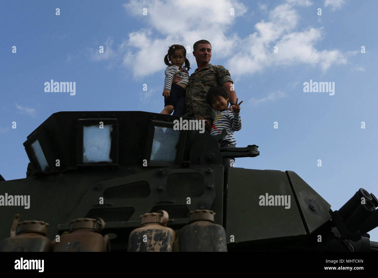 U.S. Marine Lance Cpl. Chaz Agen takes a break with two children on top ...