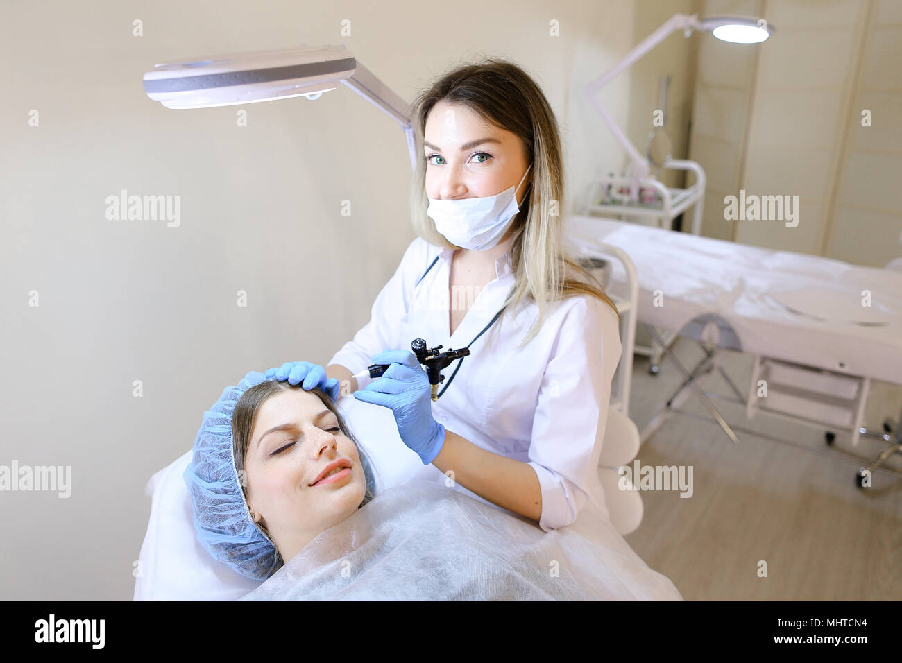 Female getting qualified permanent makeup procedure by cosmetologist ...