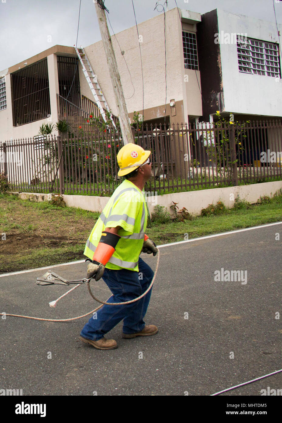 A line worker tosses a guide rope over an existing cable. He will use ...