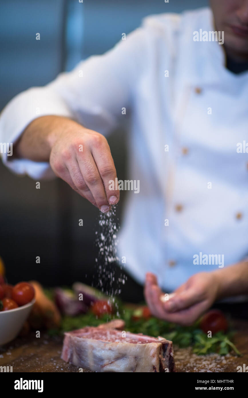 Master Chef hands putting salt on juicy slice of raw steak with ...