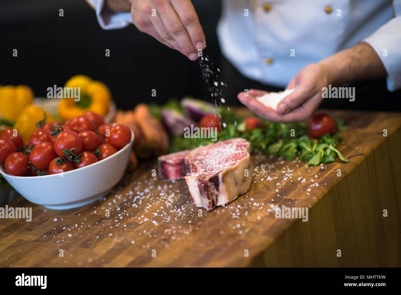 Master Chef hands putting salt on juicy slice of raw steak with ...