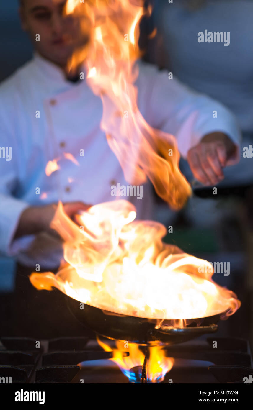 Chef cooking and doing flambe on food in restaurant kitchen Stock Photo ...