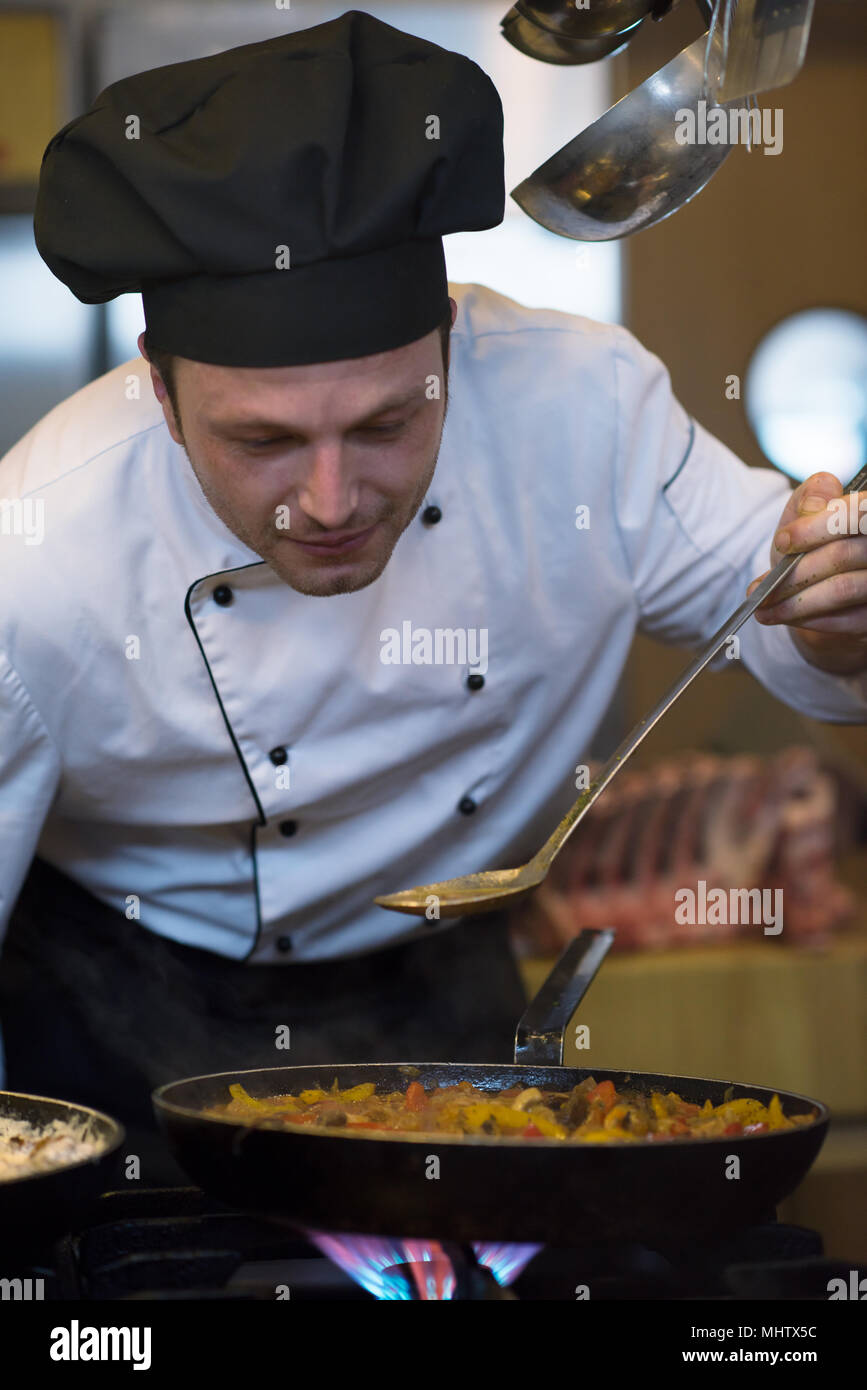 Handsome chef tasting food with spoon at the restaurant kitchen Stock ...