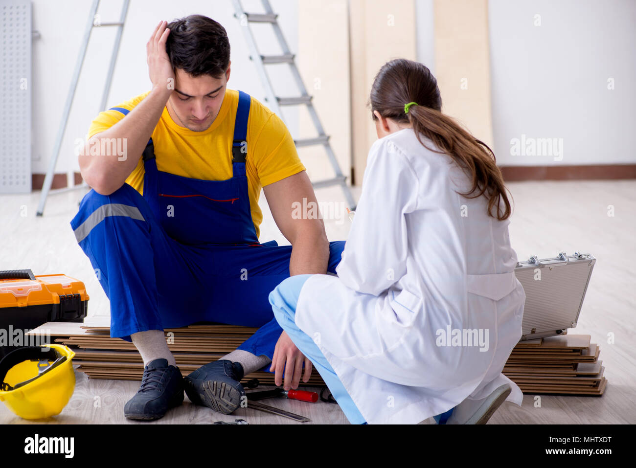 Doctor helping injured worker at construction site Stock Photo - Alamy