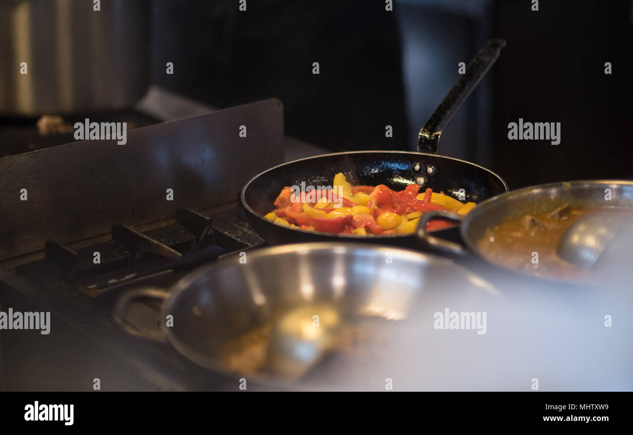 Young male chef flipping vegetables in wok at commercial kitchen Stock ...