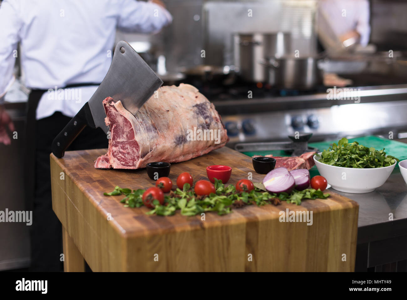 chef using ax while cutting big piece of beef on wooden board in ...