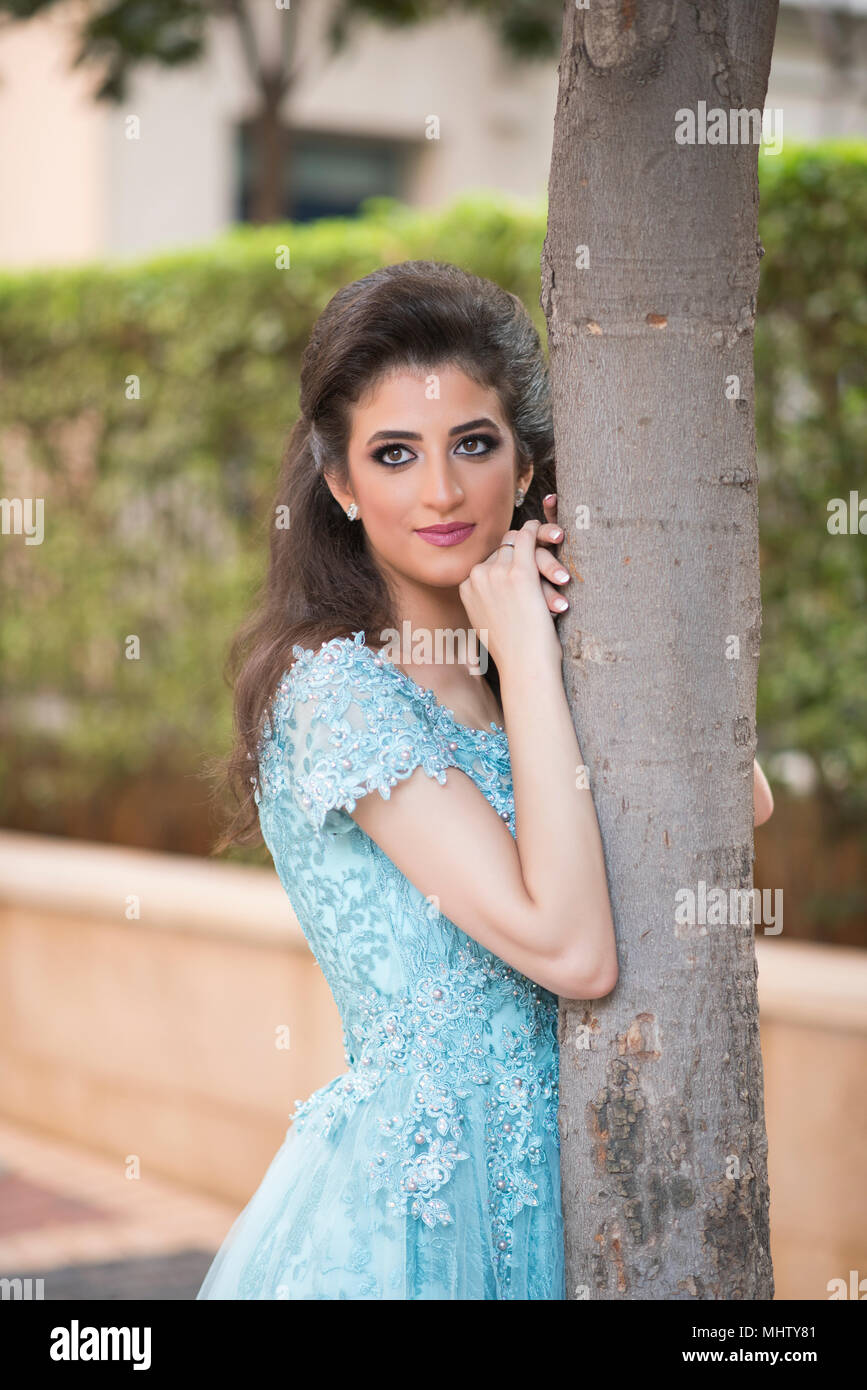 Beautiful woman leaning against a tree Stock Photo - Alamy