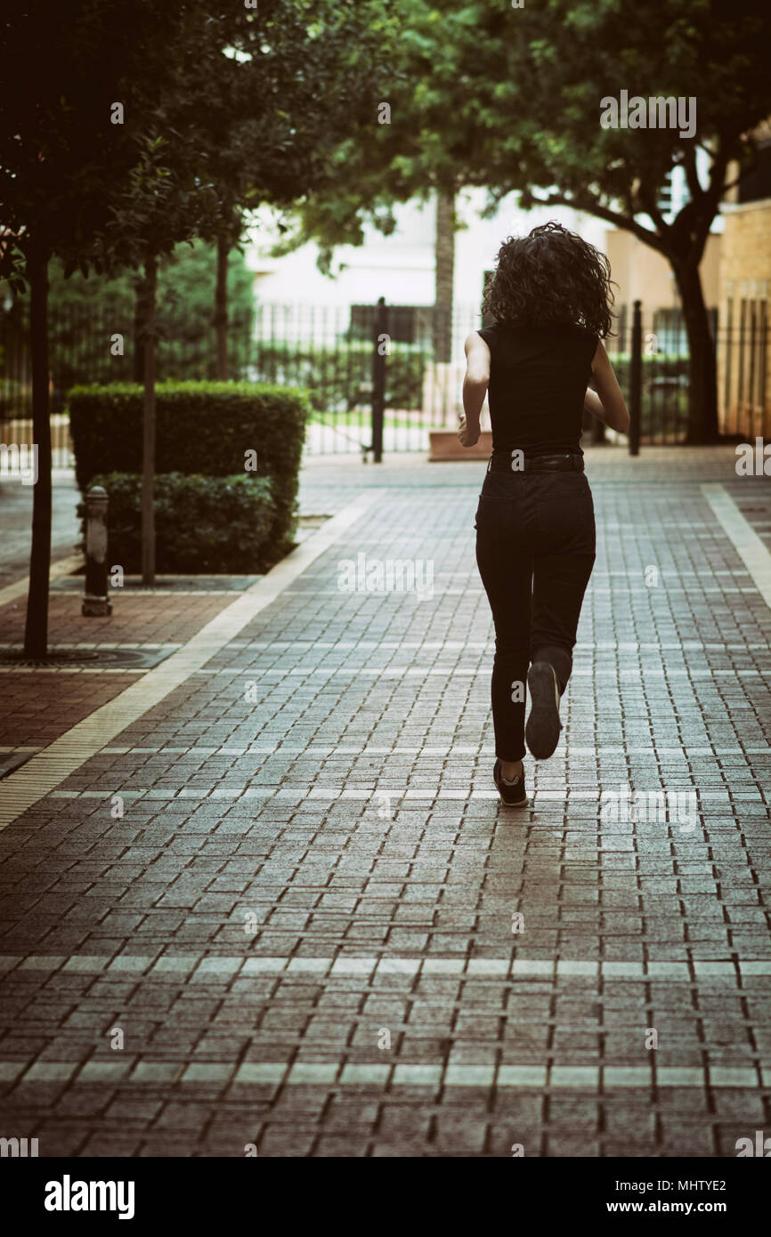 Rear view of a young woman running away Stock Photo - Alamy