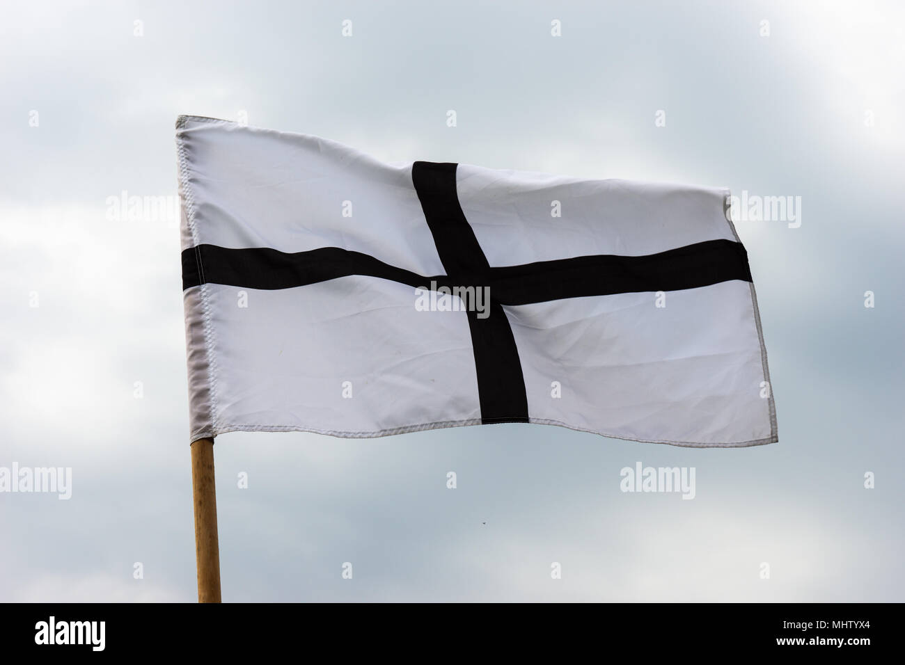 White medieval flag with a black cross waves in the wind against the ...