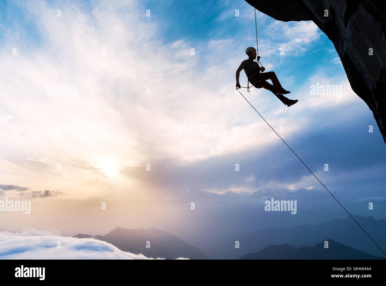 Middle-aged man climbing over a cliff Stock Photo - Alamy