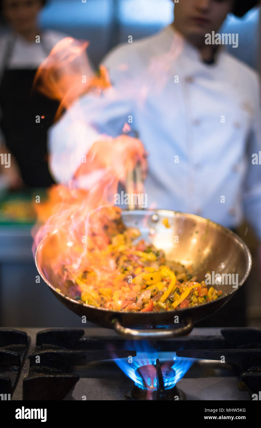Chef cooking and doing flambe on food in restaurant kitchen Stock Photo ...