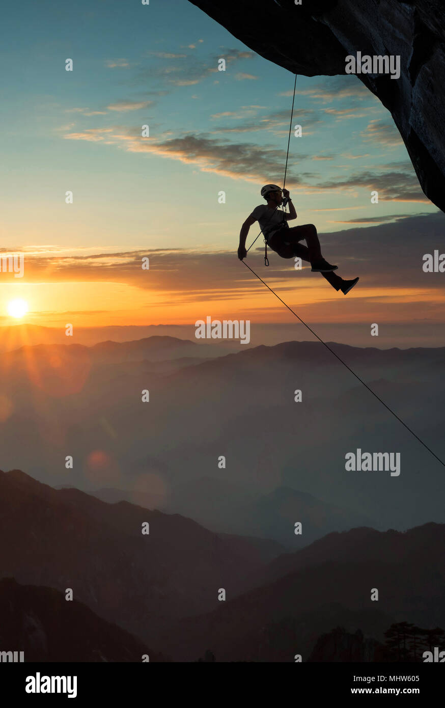 Middle-aged man climbing over a cliff Stock Photo - Alamy