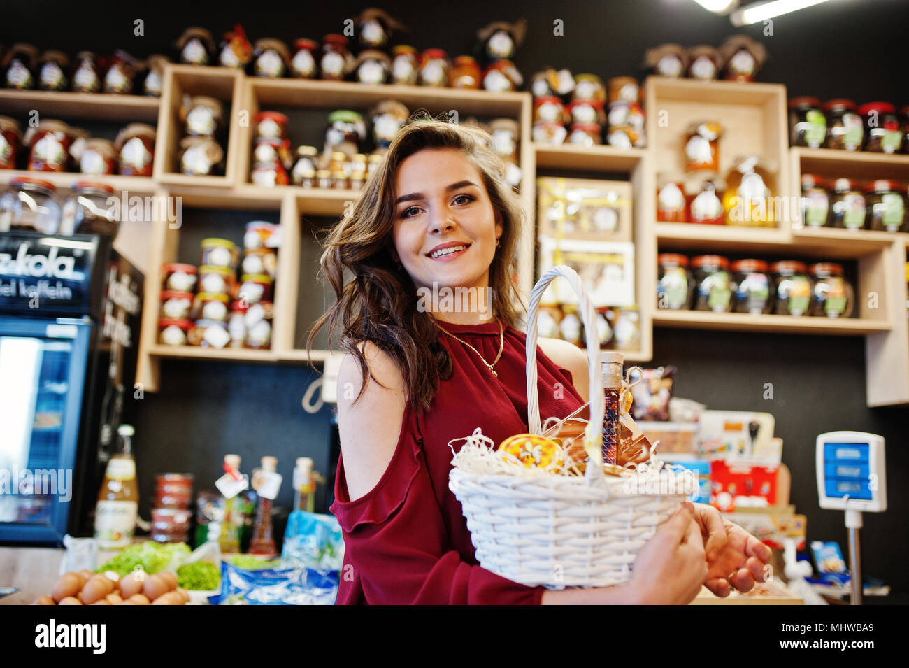Girl in red holding different products on basket at deli store Stock ...