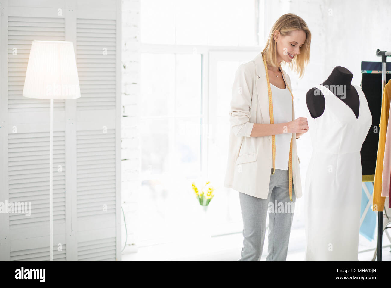 Successful female dressmaker esteeming dress Stock Photo - Alamy