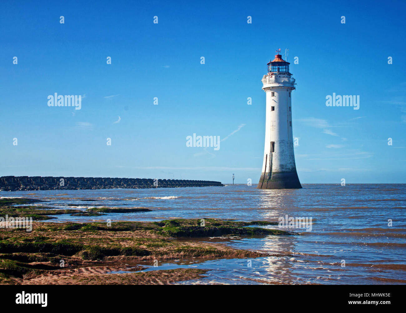 Perch Rock lighthouse, reflected in the incoming tide at New Brighton ...