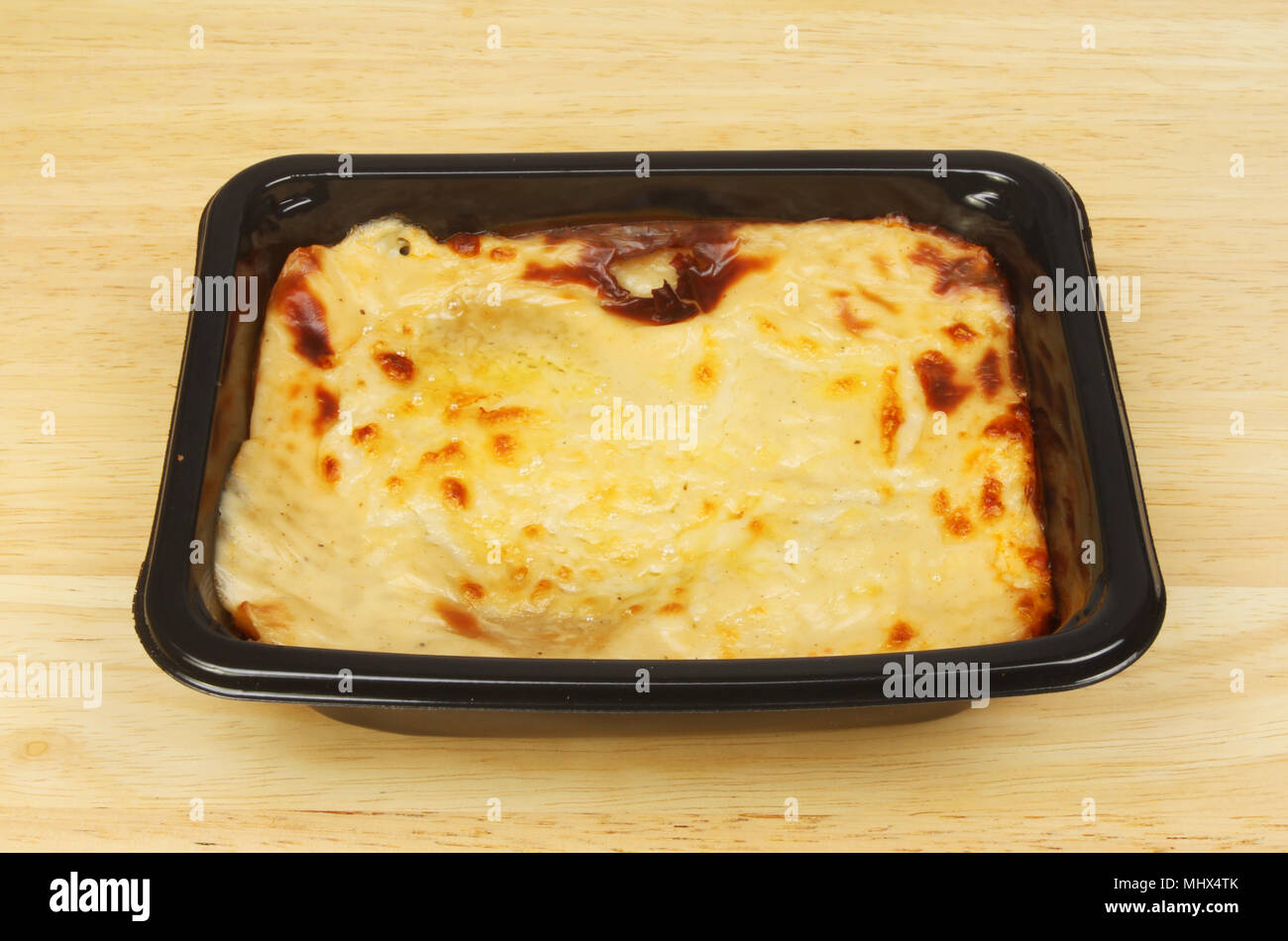 Lasagna in a plastic carton on a wooden worktop Stock Photo - Alamy
