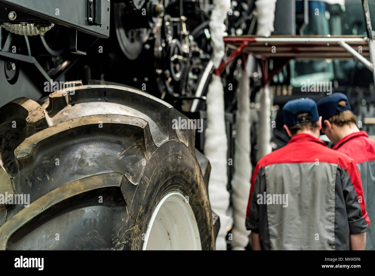 Worker assembles tractor or combine harvester at large machinery plant ...