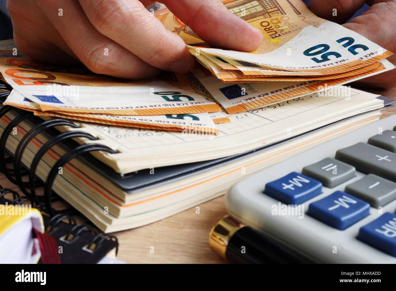 Man counting euro banknotes. Desk with calculator, ledger and euros ...