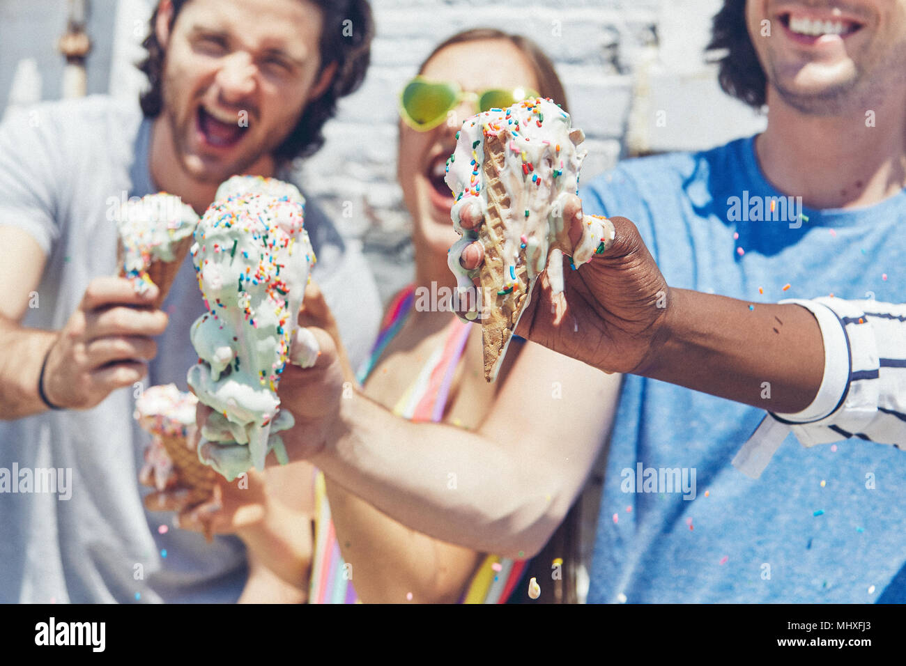 Young woman and men holding up melting ice cream cones, laughing Stock ...