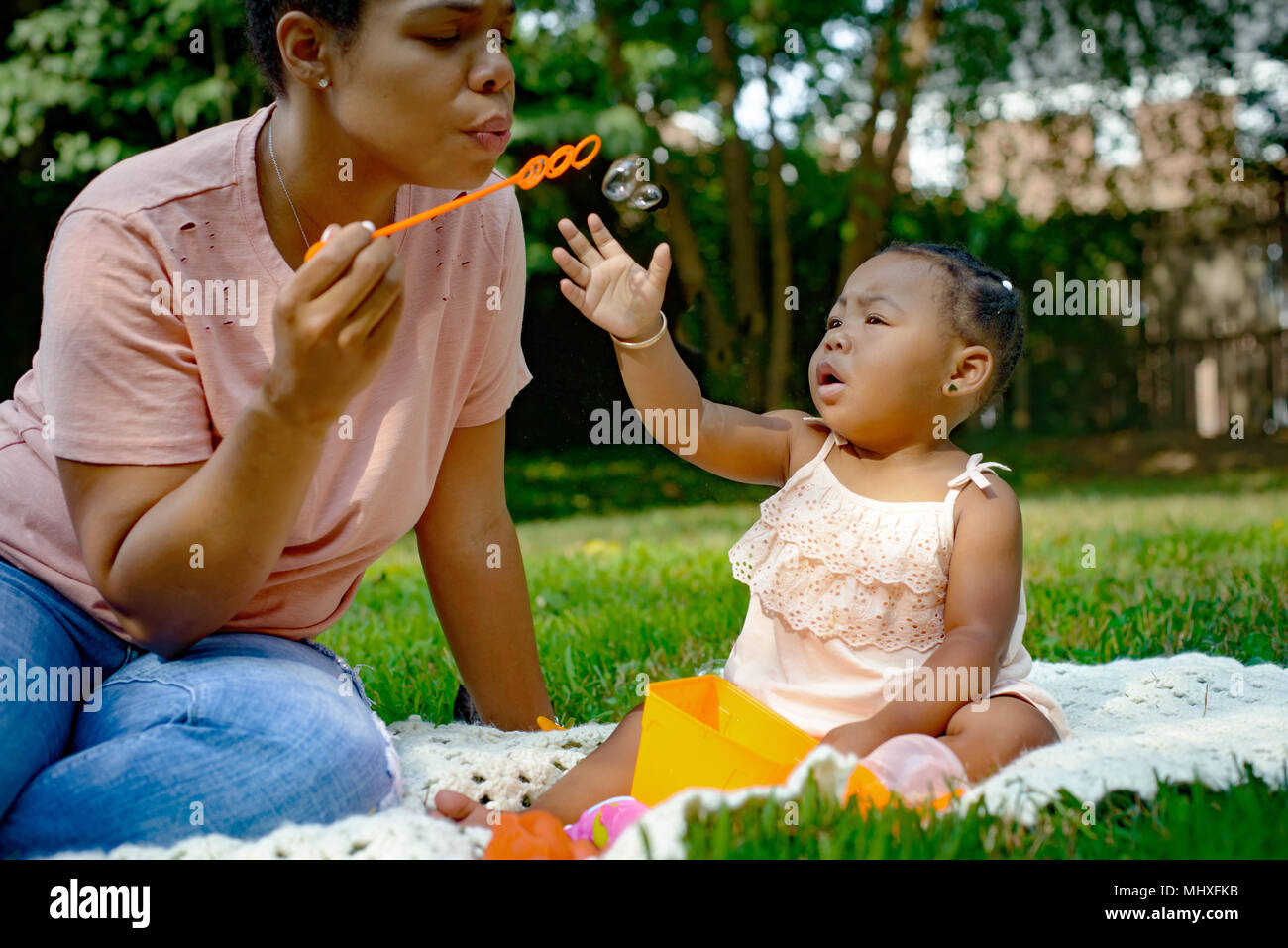 Mid adult woman blowing bubbles in garden for baby daughter Stock Photo ...