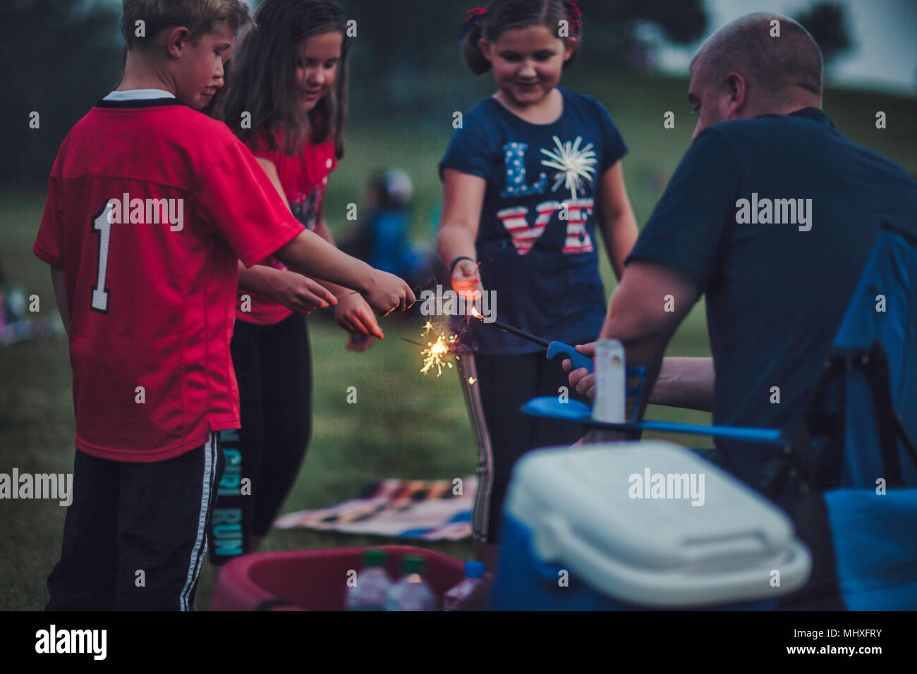 Father lighting sparklers for group of children Stock Photo - Alamy