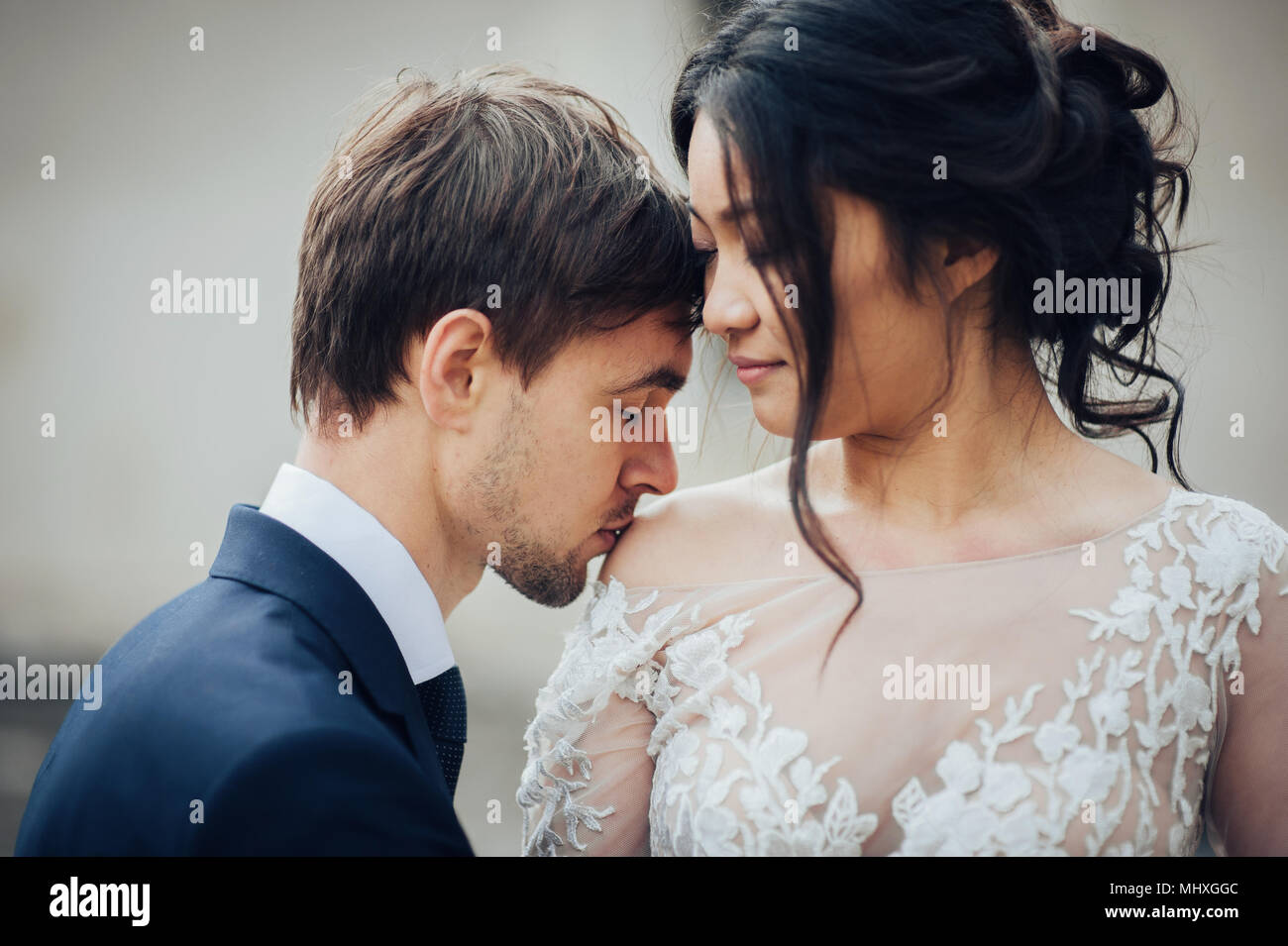 Groom tenderly kissing bride in shoulder Stock Photo - Alamy