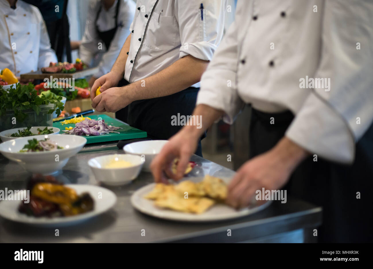 Professional team cooks and chefs preparing meal at busy hotel or ...
