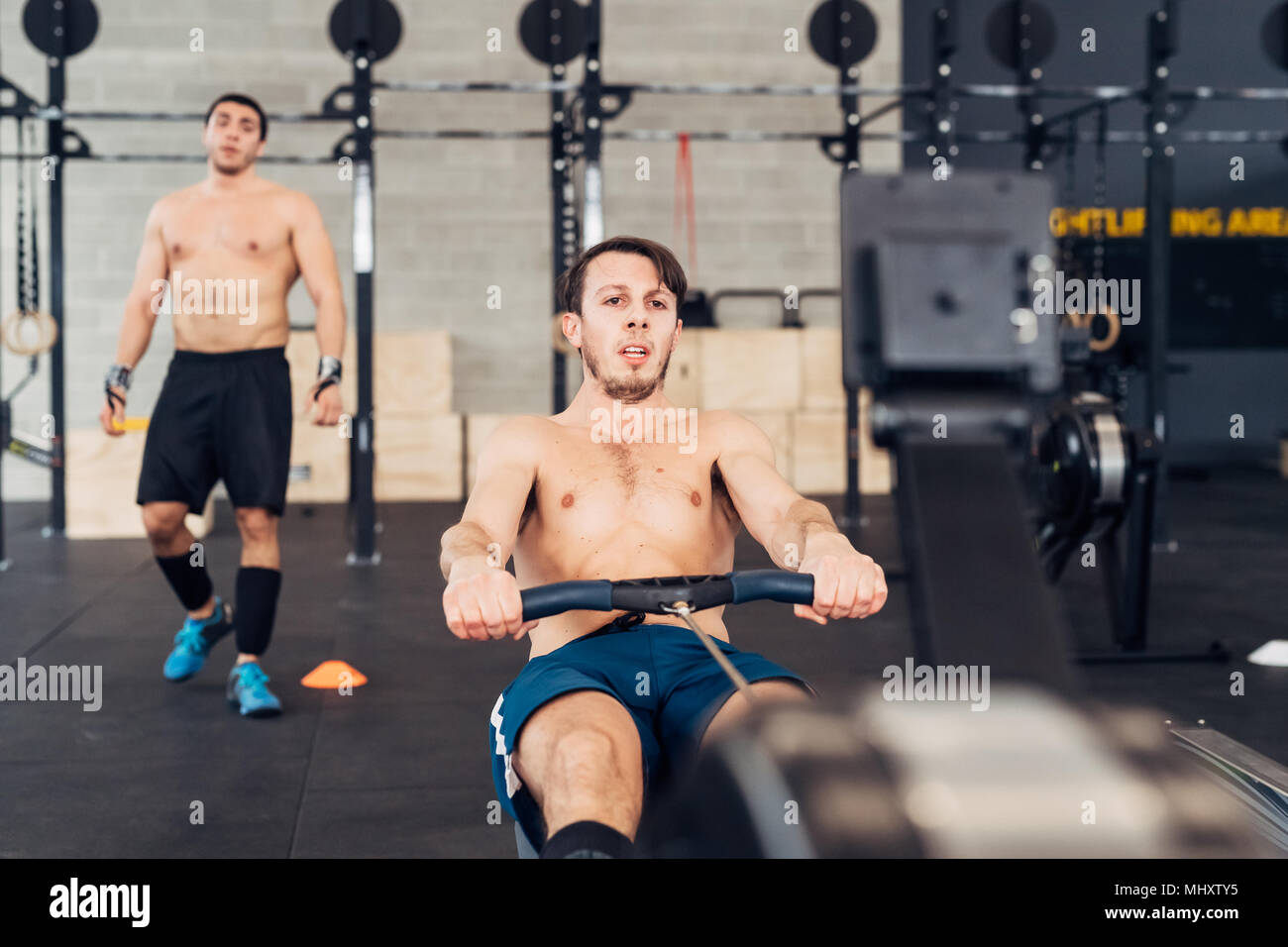 Man in gym using rowing machine Stock Photo - Alamy