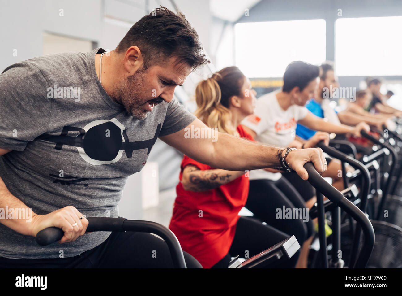 People in gym using exercise bikes Stock Photo - Alamy