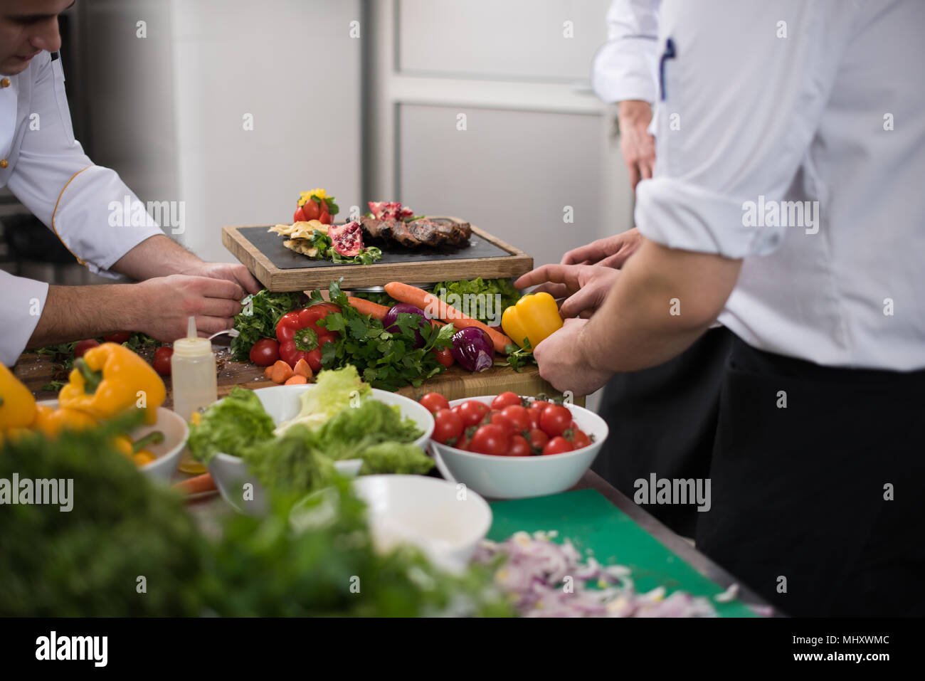 Professional team cooks and chefs preparing meal at busy hotel or ...