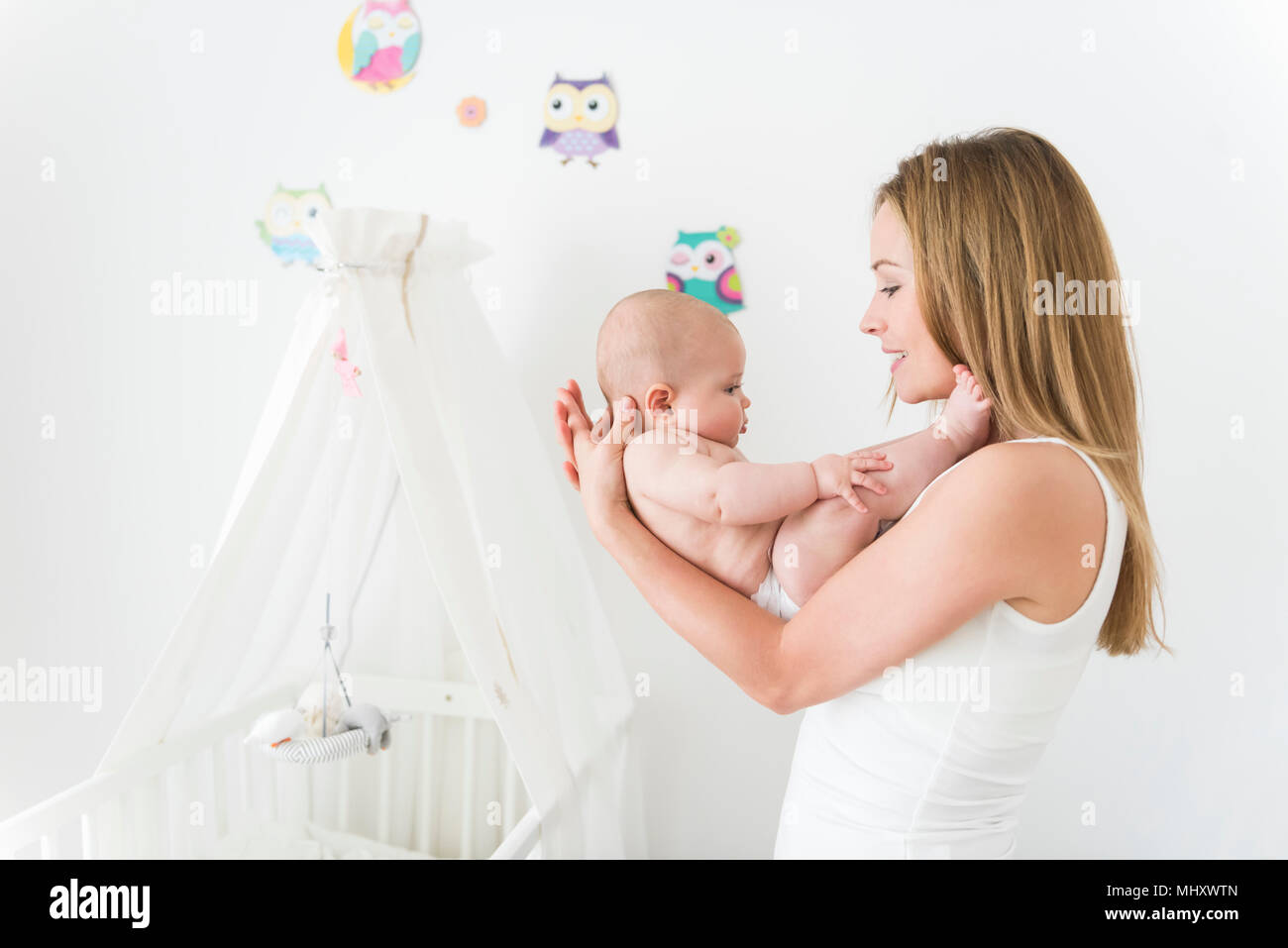 Mother cradling baby in nursery room Stock Photo - Alamy