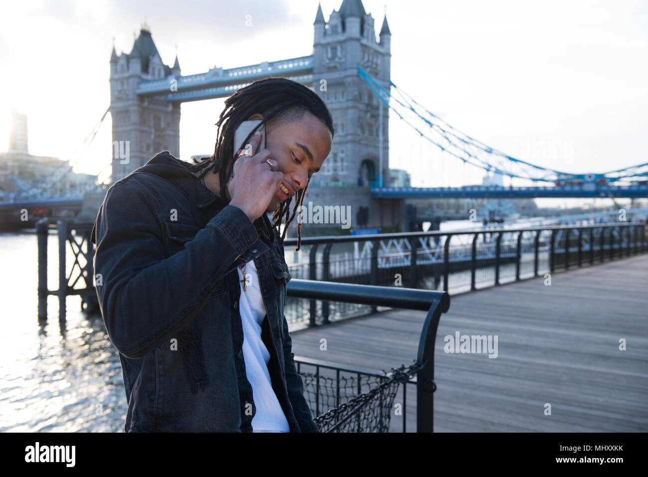 Young man outdoors, using smartphone, Tower Bridge in background ...