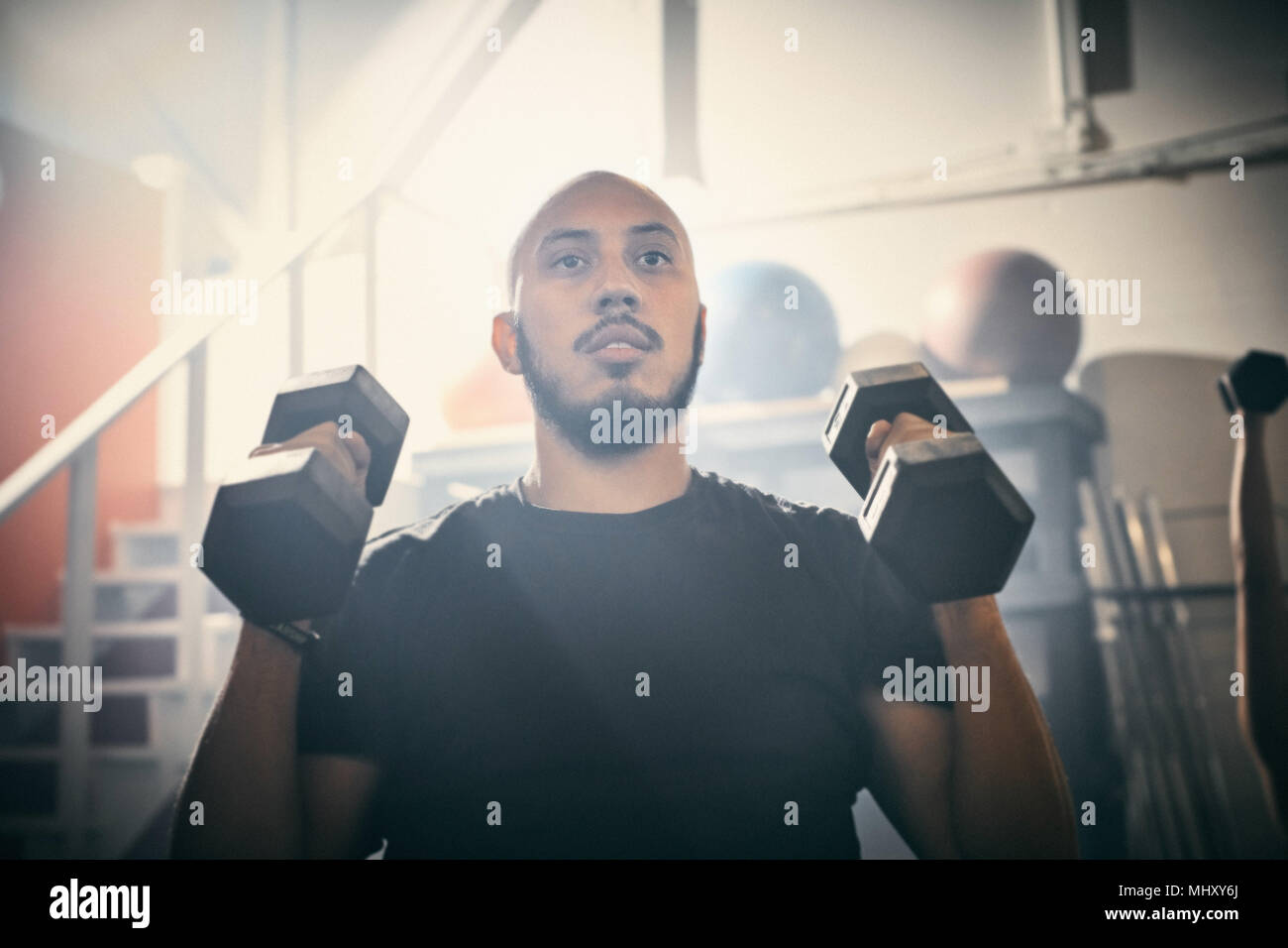 Man using dumbbells in gym Stock Photo - Alamy