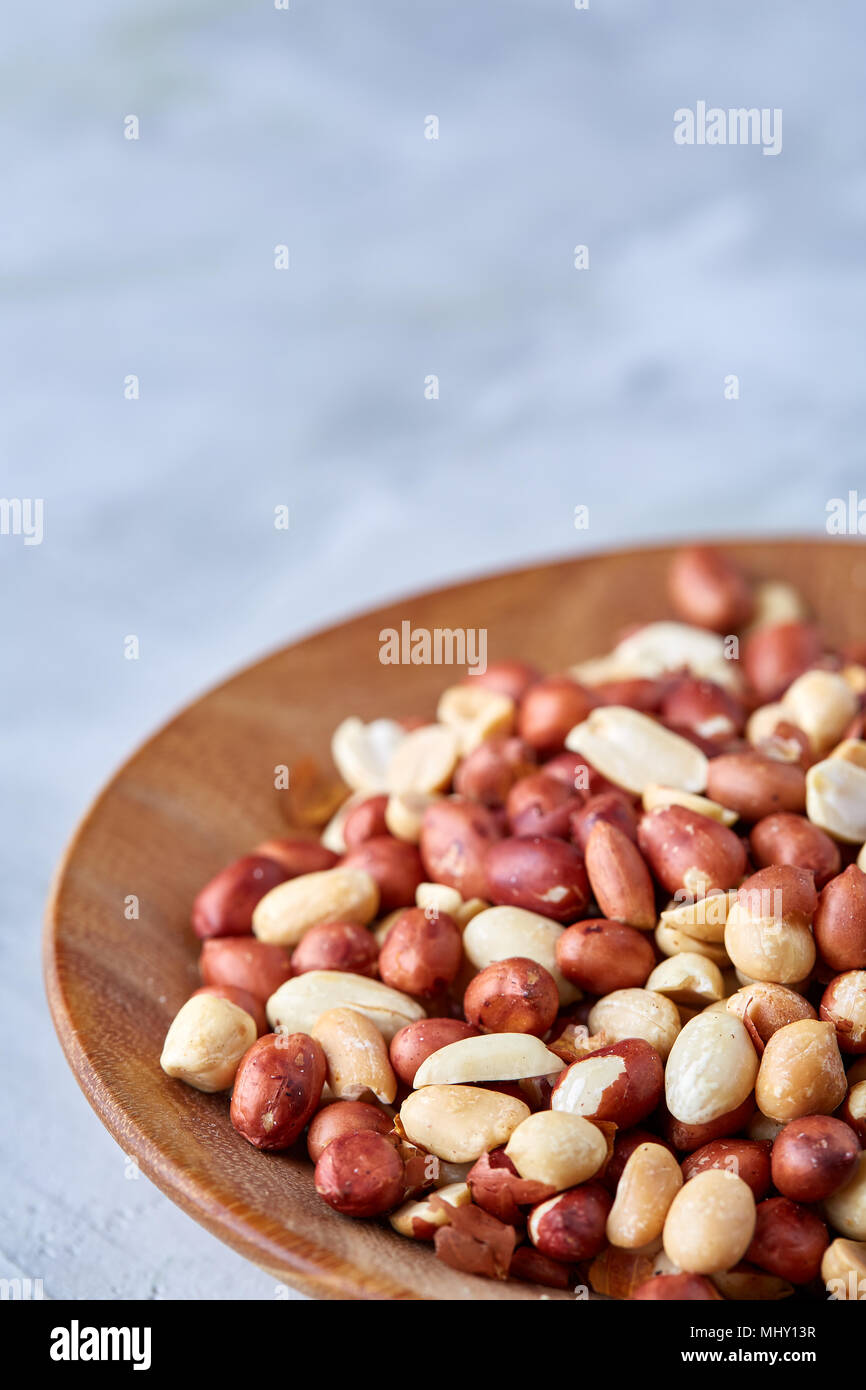 Mix of raw shelled peanuts in wooden plate isolated over white textured ...