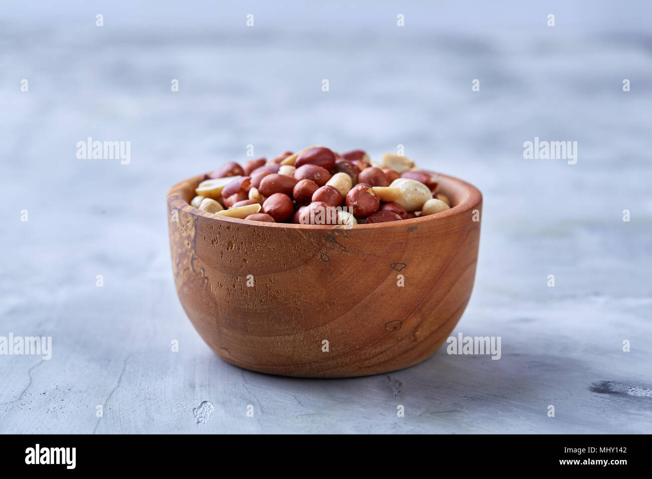 Mix of raw shelled peanuts in wooden plate isolated over white textured ...