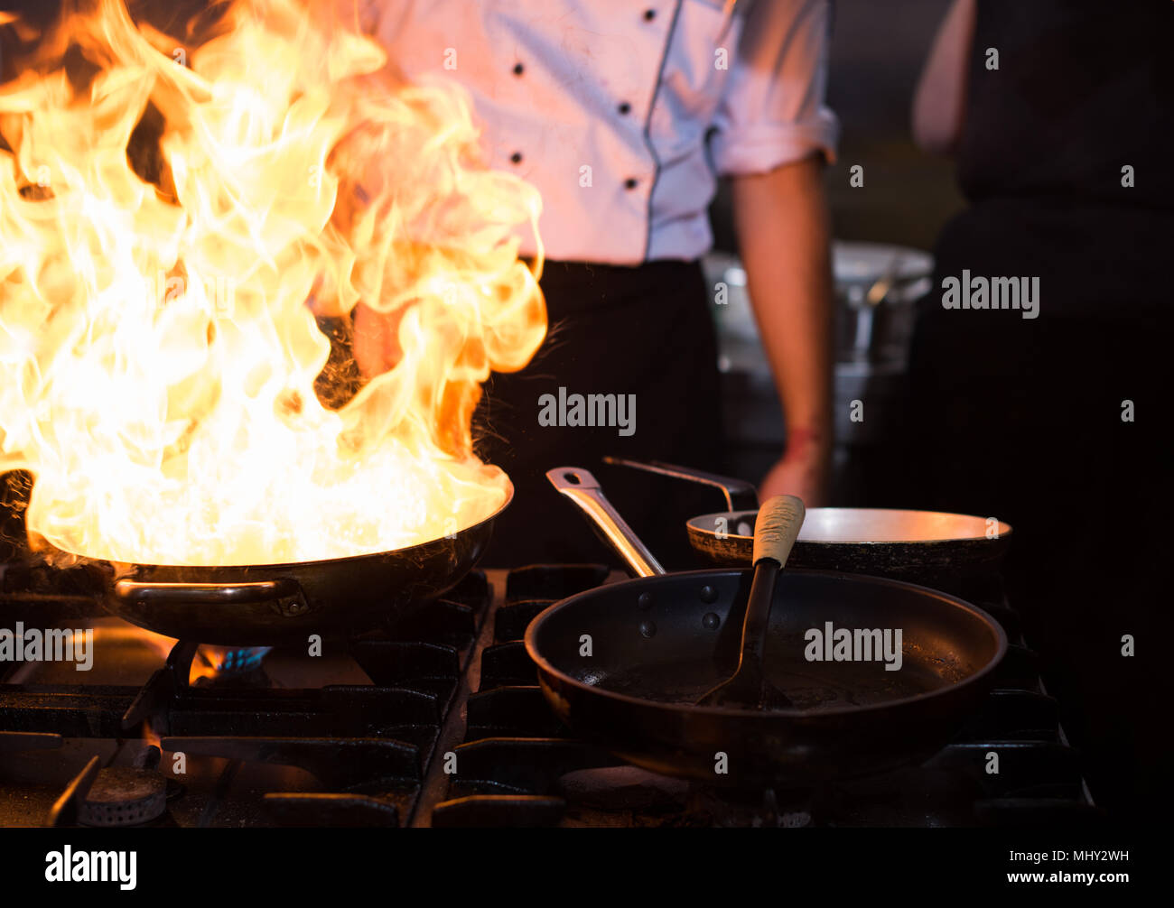 Chef cooking and doing flambe on food in restaurant kitchen Stock Photo ...