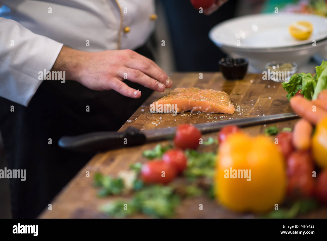 Chef hands preparing marinated Salmon fish fillet for frying in a ...