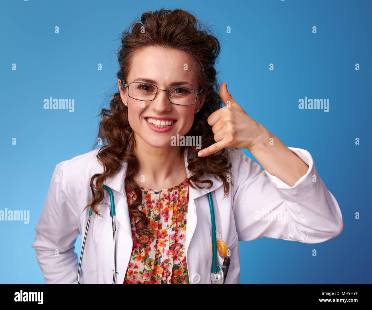 smiling paediatrist woman in white medical robe showing call me gesture ...