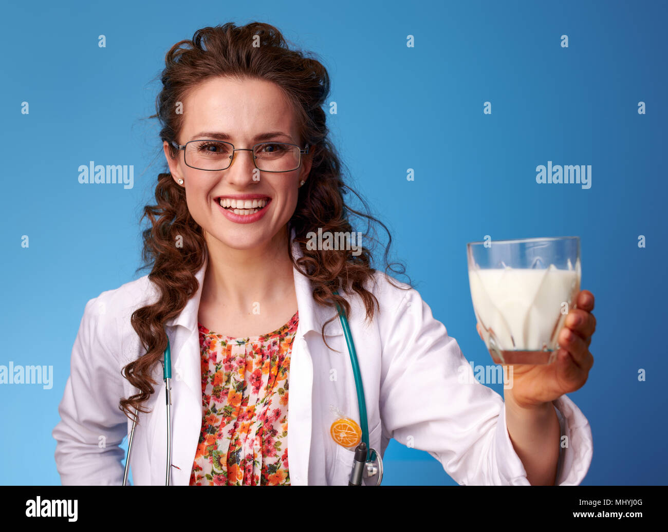 smiling pediatrist doctor in white medical robe giving a glass of milk ...