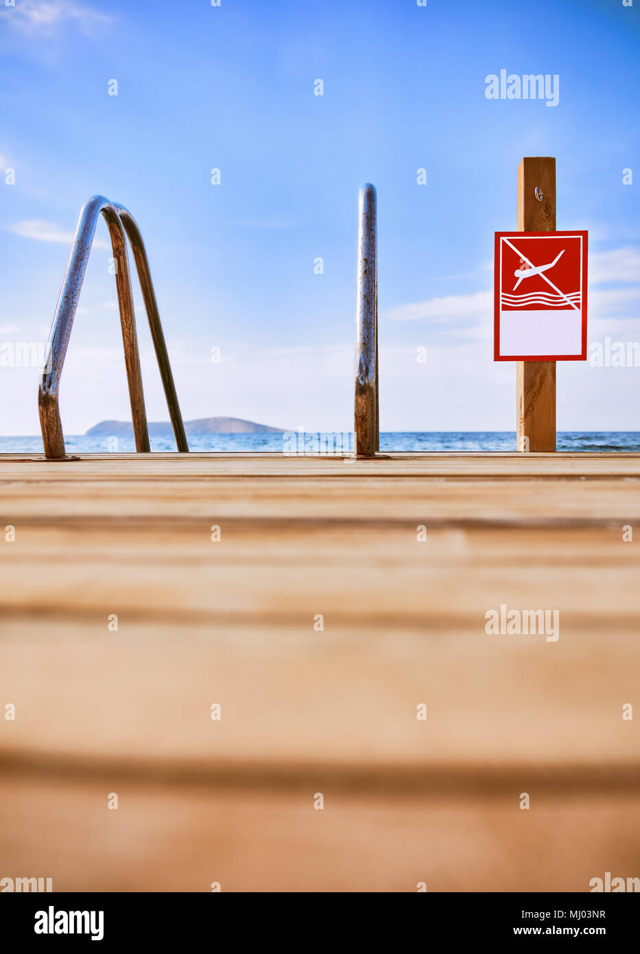 Red no diving sign with copy space on a wooden pier next to a sea ...