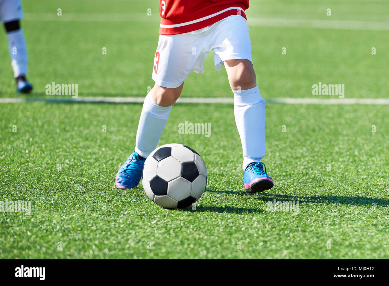 Foot of a child football player and ball on the football field Stock ...