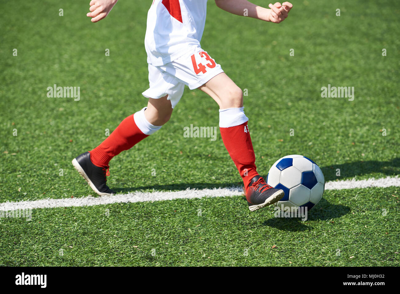 Foot of a child football player and ball on the football field Stock ...