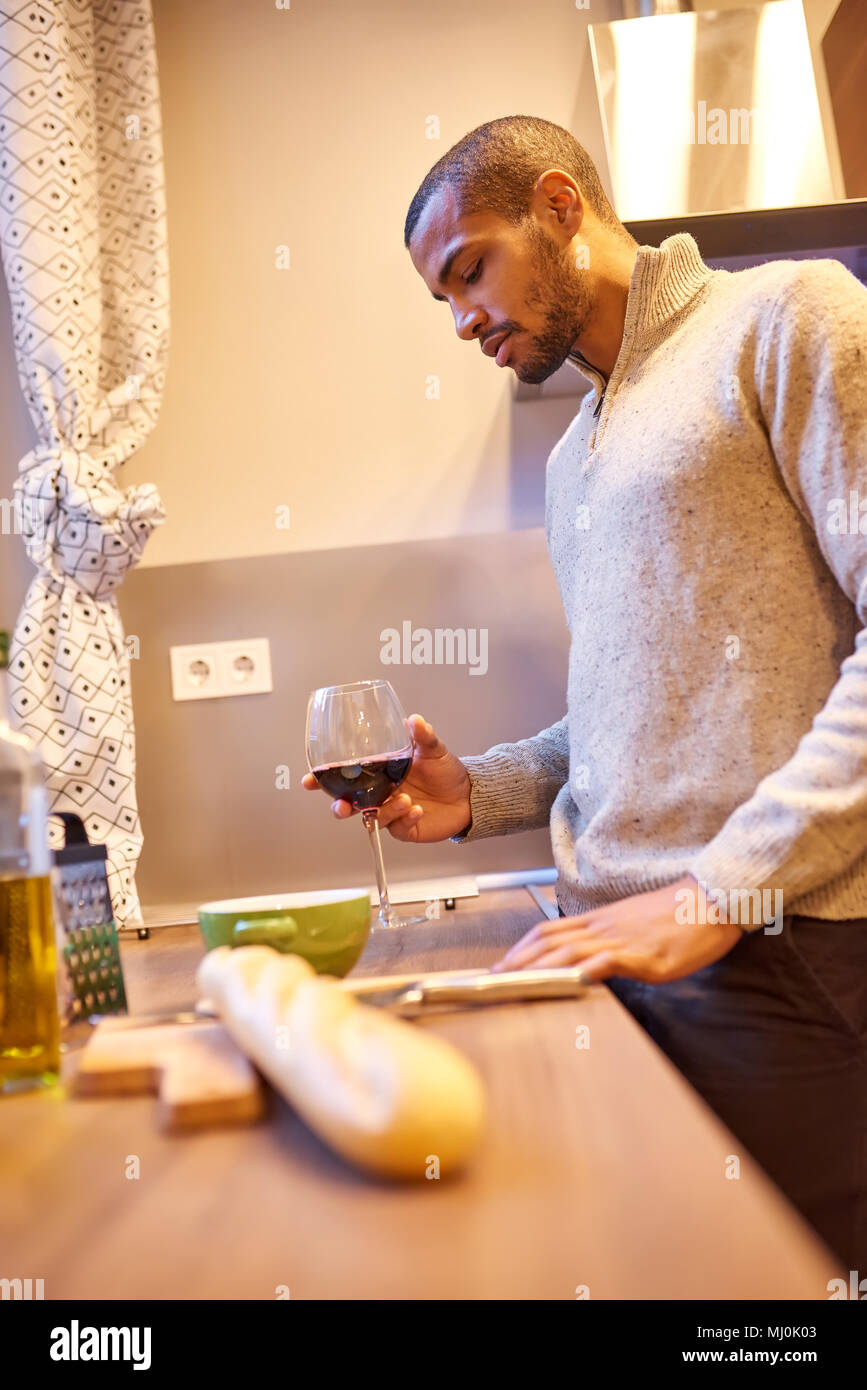 A serious handsome young man drinking wine in the kitchen Stock Photo ...