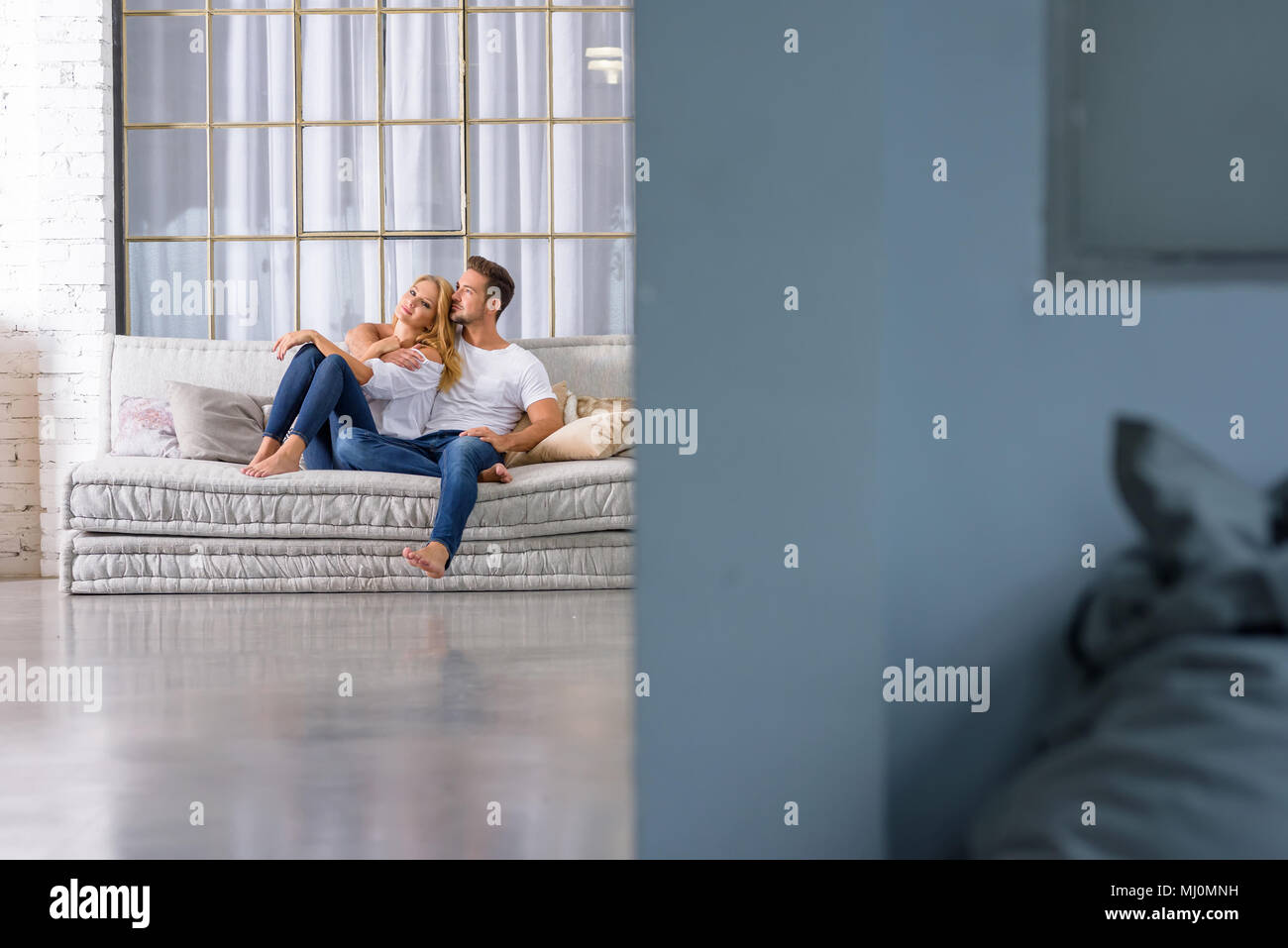 A beautiful young couple sitting on the sofa and cuddling Stock Photo ...