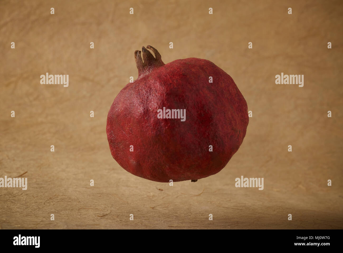 A pomegranate against handmade paper as a product Stock Photo - Alamy