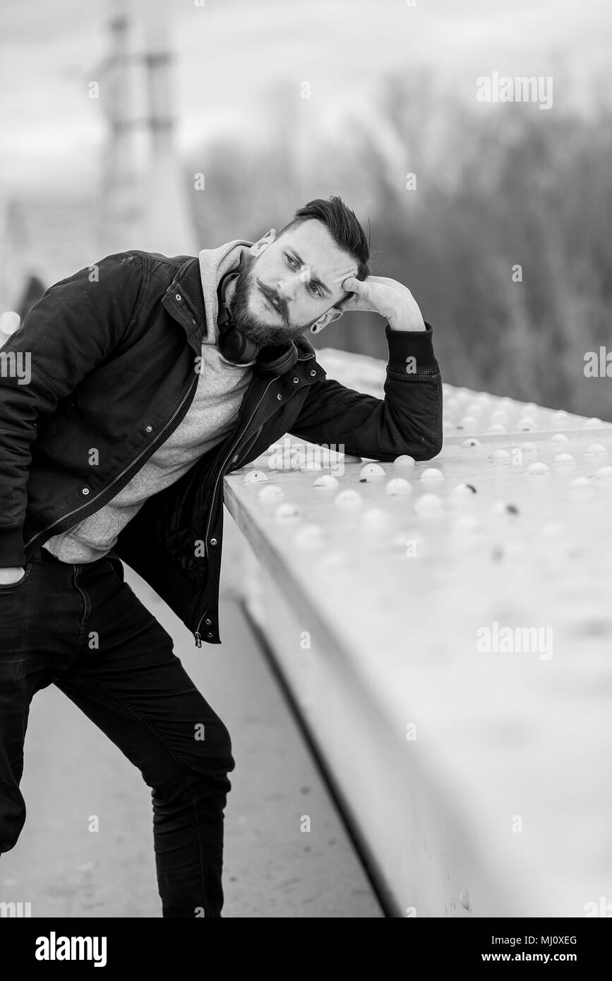 Portrait of a thinking handsome young hipster man while leaning on the ...