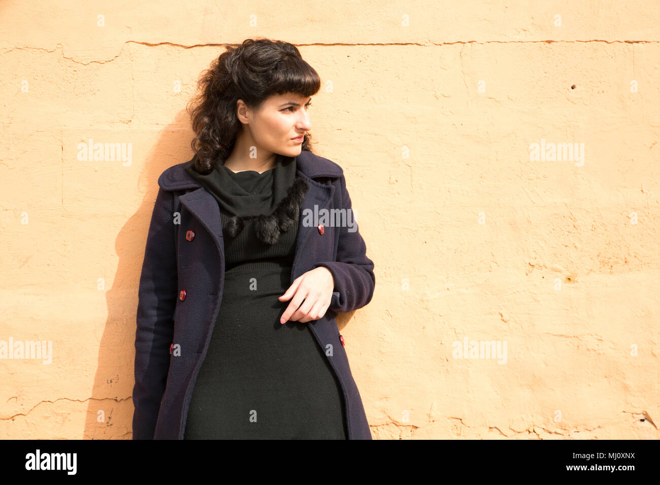 A retro styled girl waiting and leaning against a wall Stock Photo - Alamy