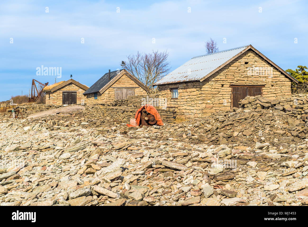 Small limestone fishing sheds in a row on a very rocky shore on the ...