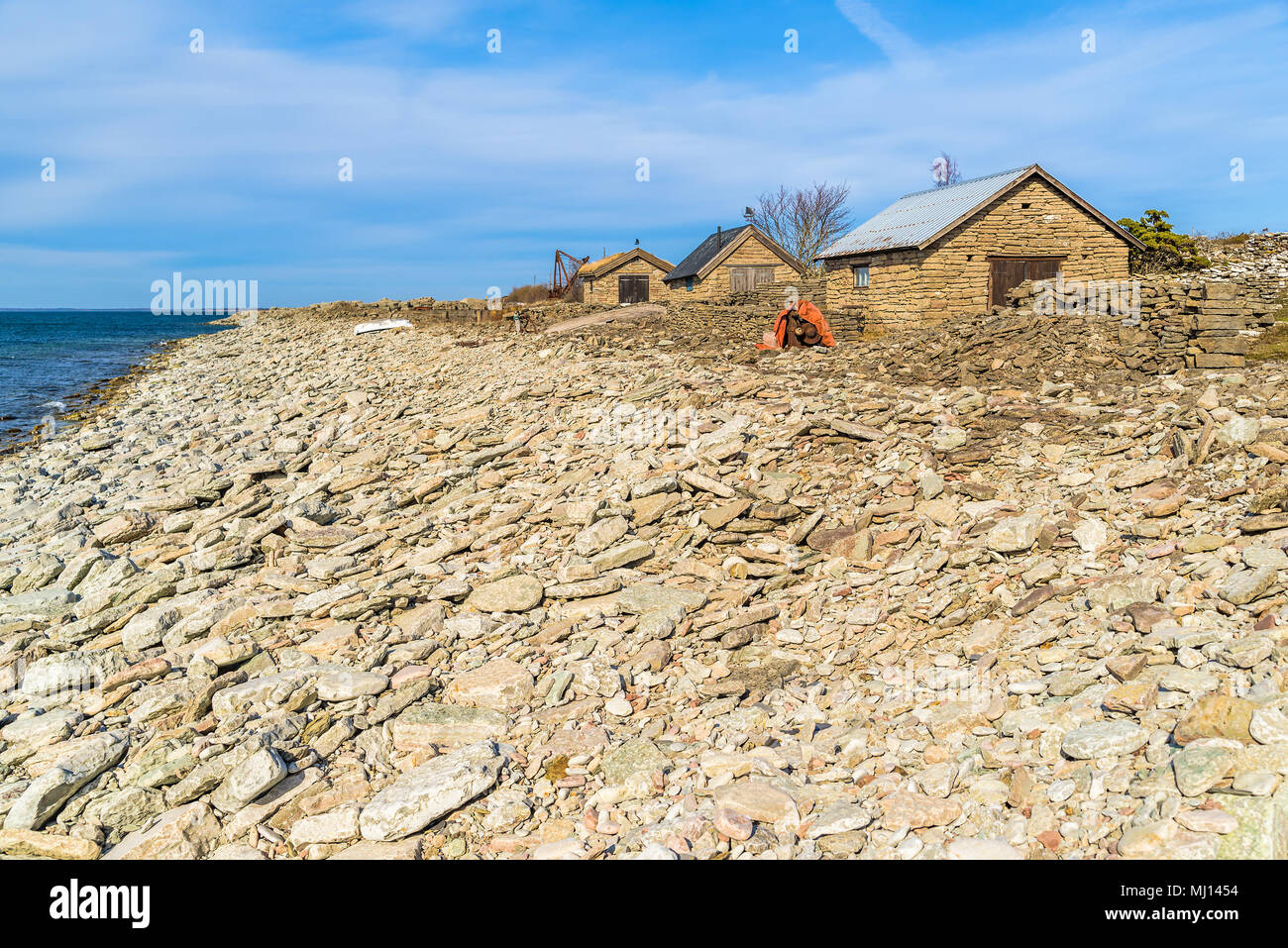 Small limestone fishing sheds in a row on a very rocky shore on the ...