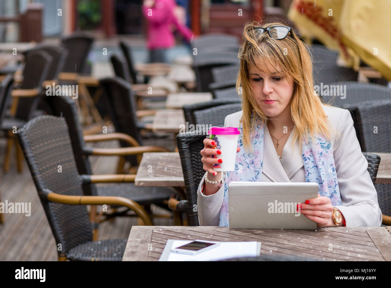A young business woman drinking tea in a cafe and working with a ...